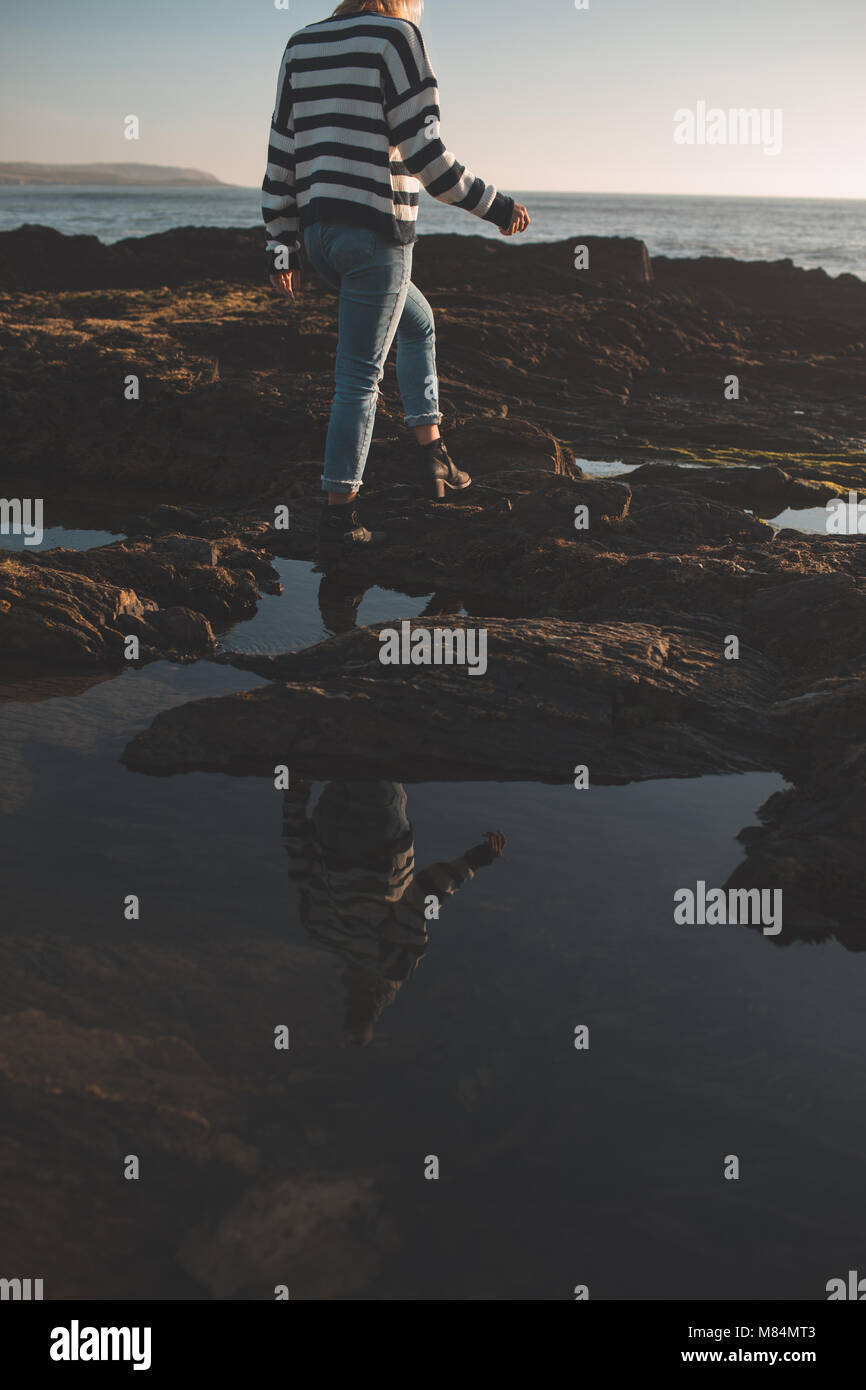 Woman walking over rock at beach Stock Photo - Alamy