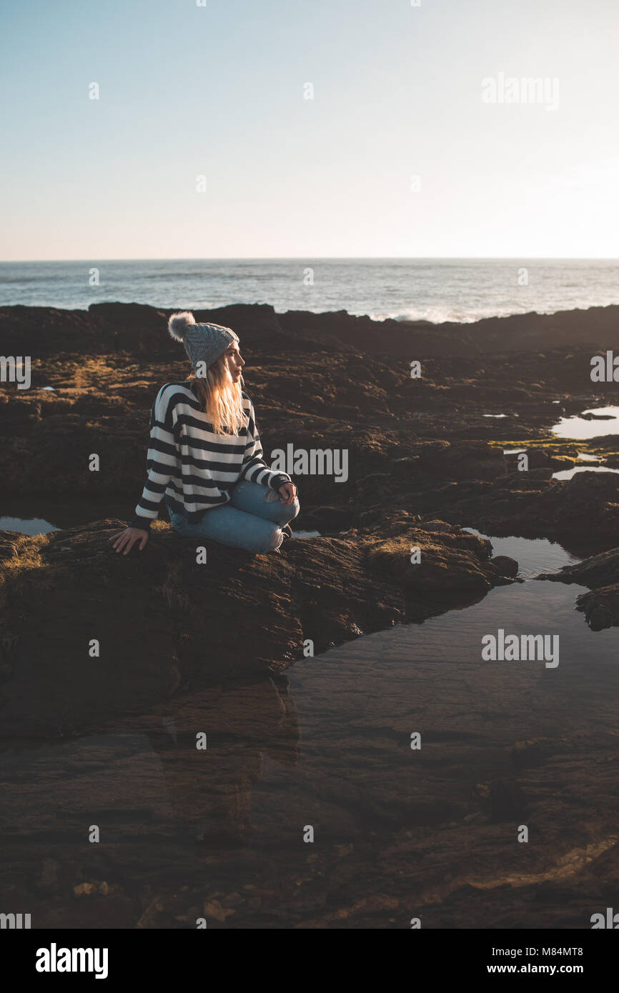 Woman sitting on rock at beach Stock Photo - Alamy