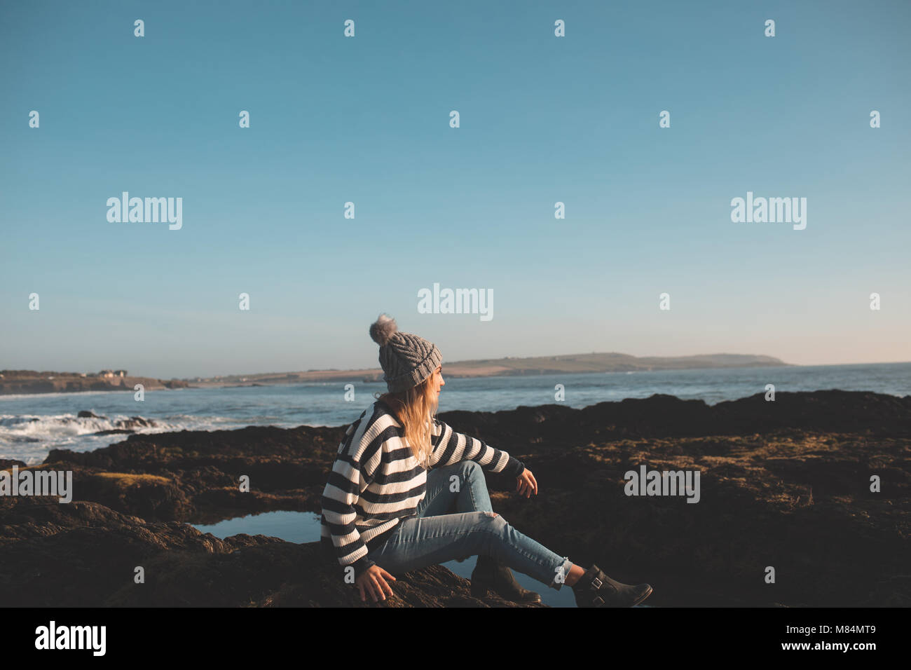 Woman sitting on rock at beach Stock Photo - Alamy