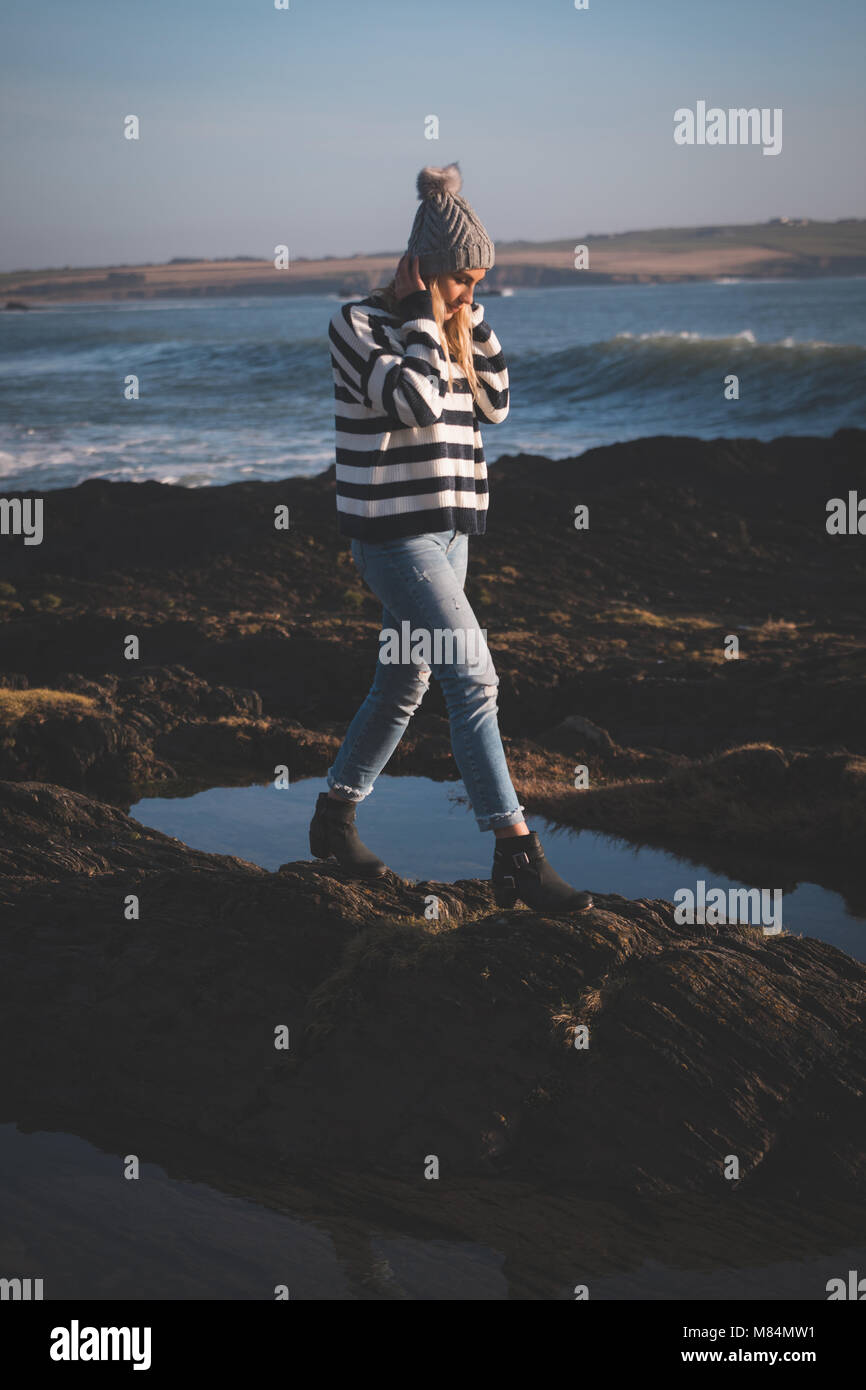 Woman walking over rock at beach Stock Photo - Alamy