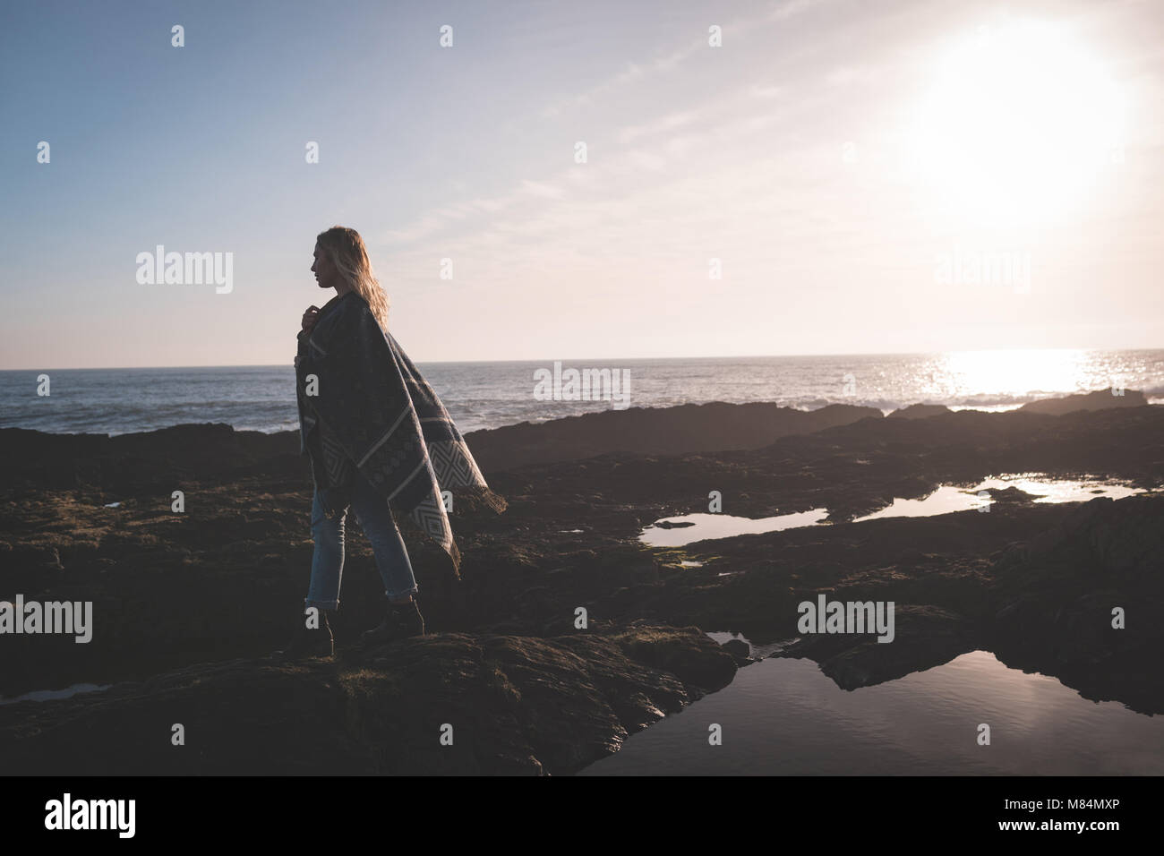 Woman walking over rock on a beach Stock Photo - Alamy