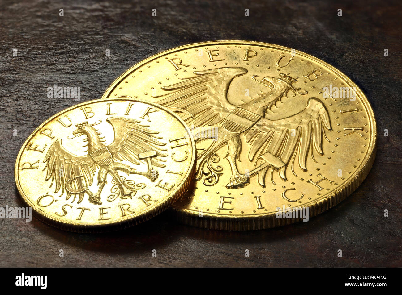 Austrian 25 and 100 Schilling gold coins on rustic wooden background ...