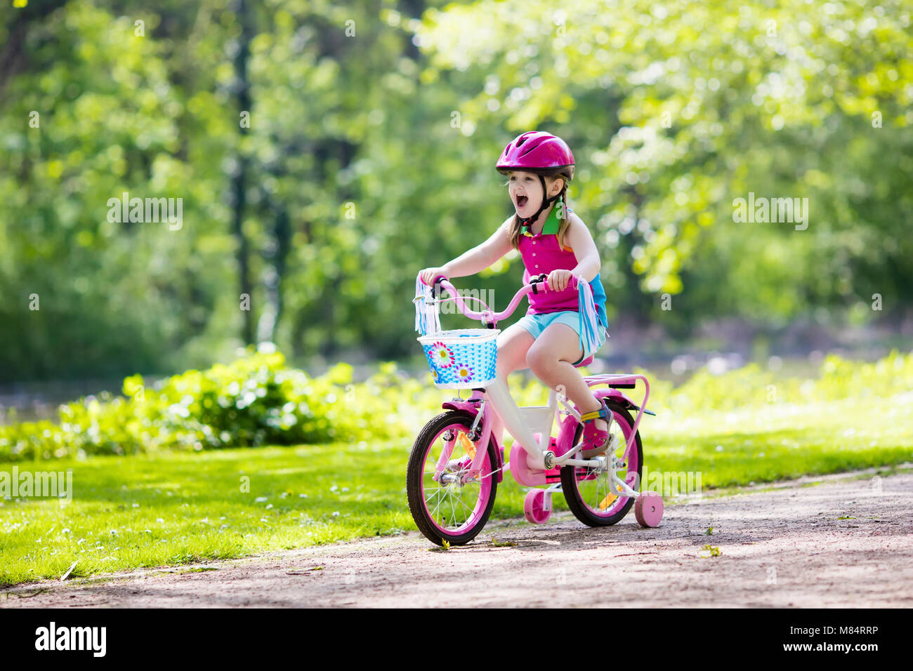 Child riding bike. Kid on bicycle in sunny park. Little girl enjoying ...