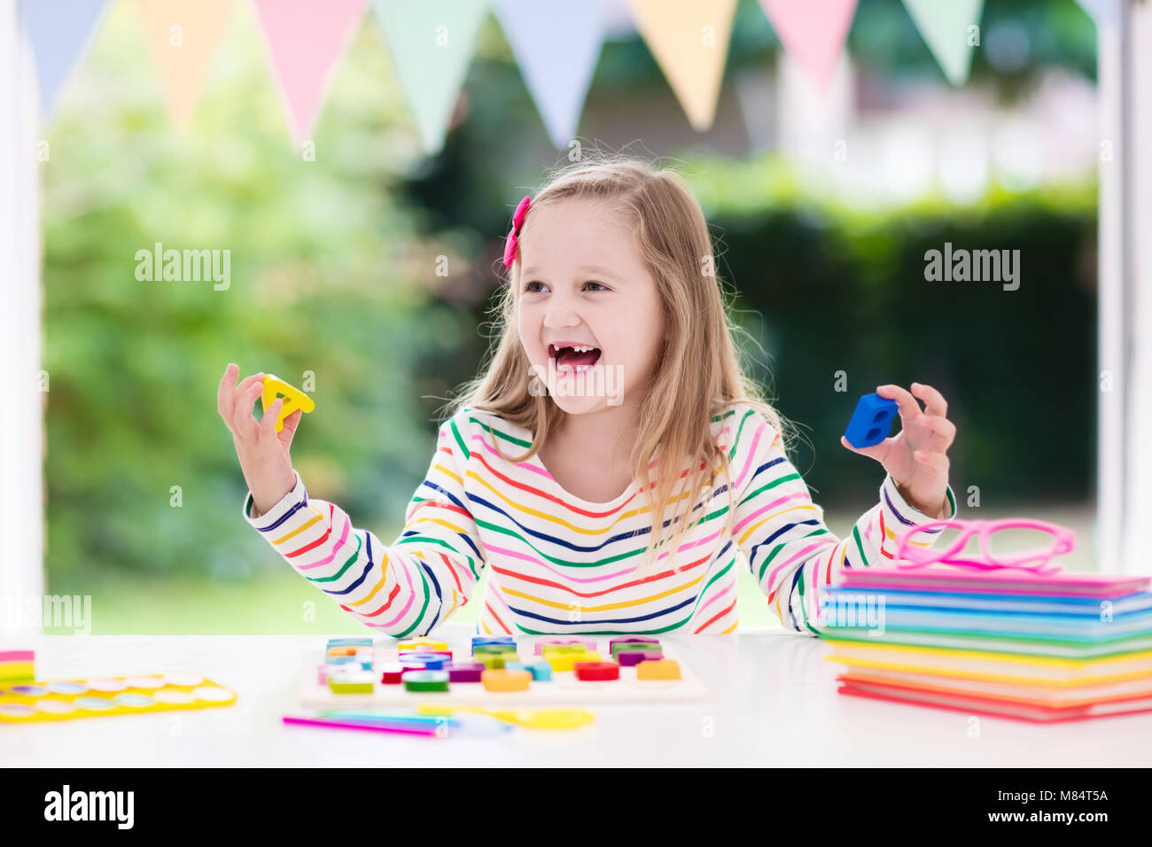 Child doing homework for school at white desk. Wooden educational abc ...