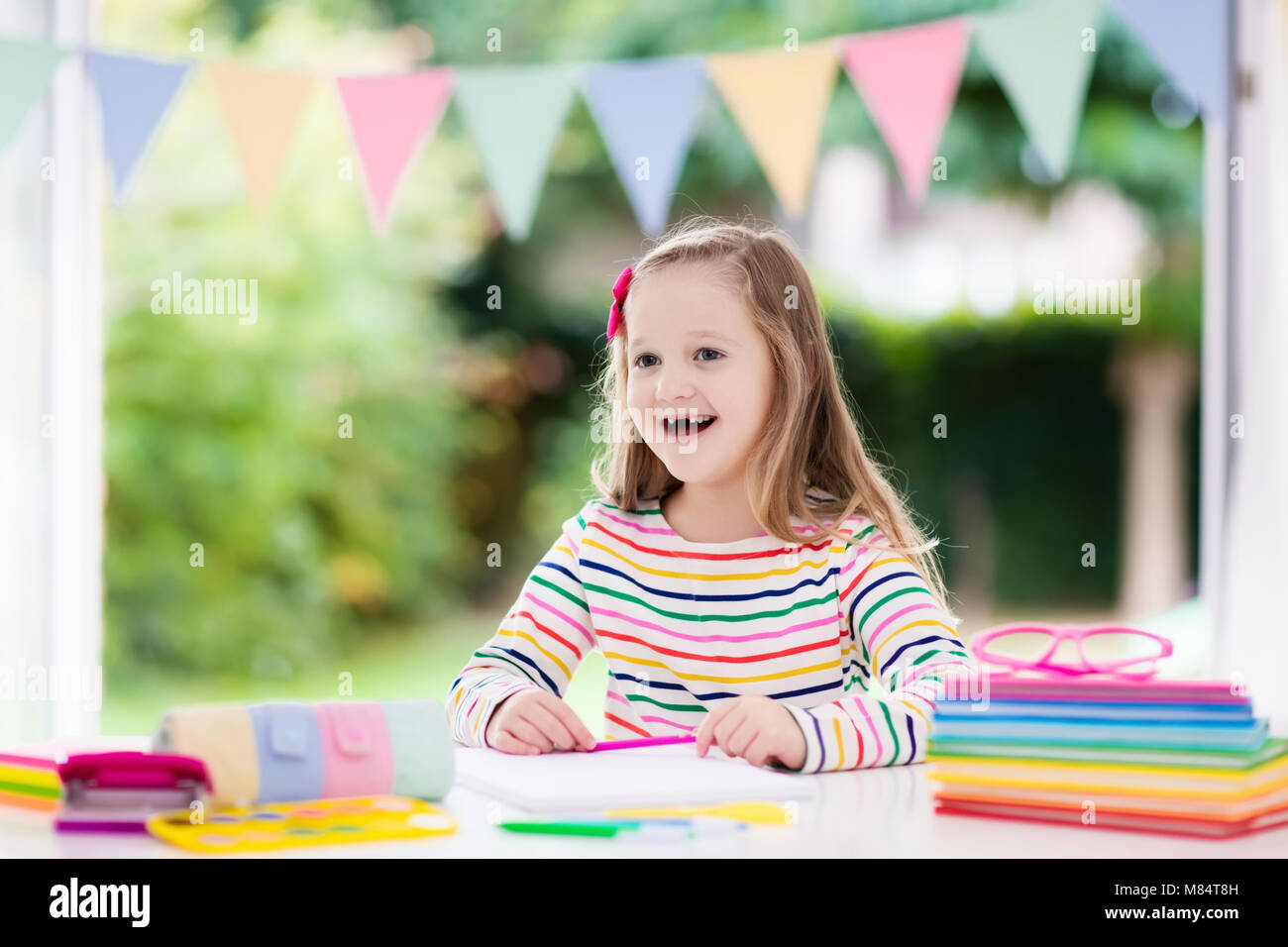 Child doing homework for school at white desk. Little girl with school ...