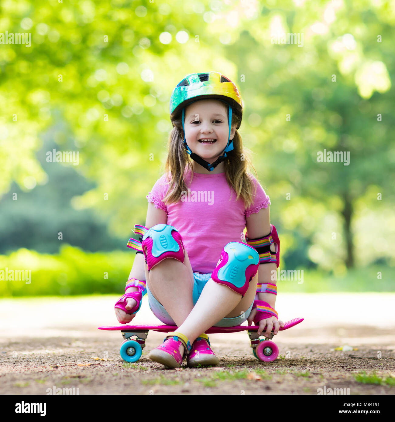 Child riding skateboard in summer park. Little girl learning to ride ...
