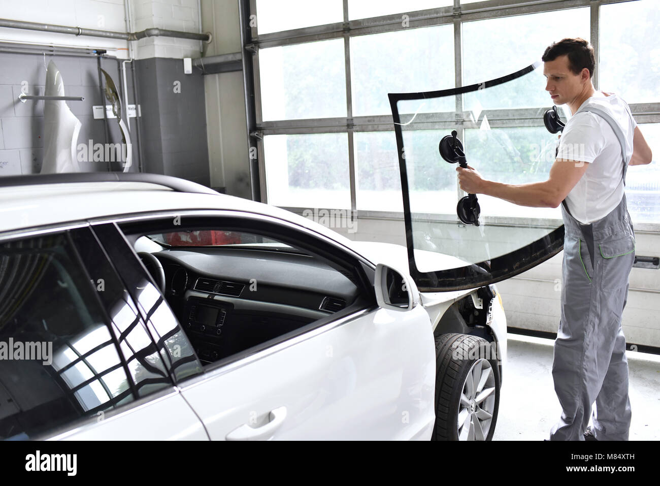 mechanic in a garage replaces defective windshield of a car Stock Photo ...