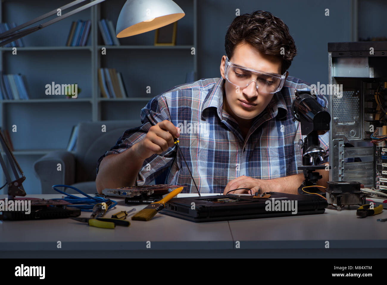 Young repair technician soldering electrical parts on motherboard Stock ...