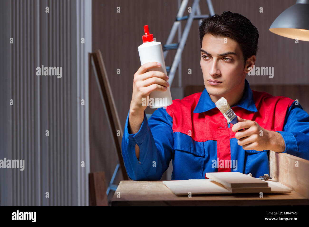 Young man gluing wood pieces together in DIY concept Stock Photo - Alamy