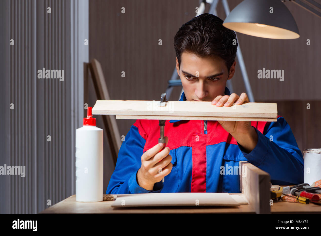 Young man gluing wood pieces together in DIY concept Stock Photo - Alamy