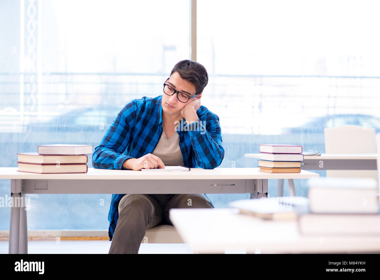 Student studying in the empty library with book preparing for exam ...