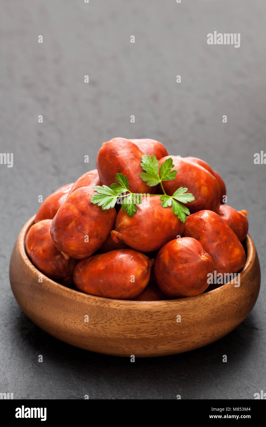 Mini chorizo sausages in wooden bowl on black stone background Stock ...