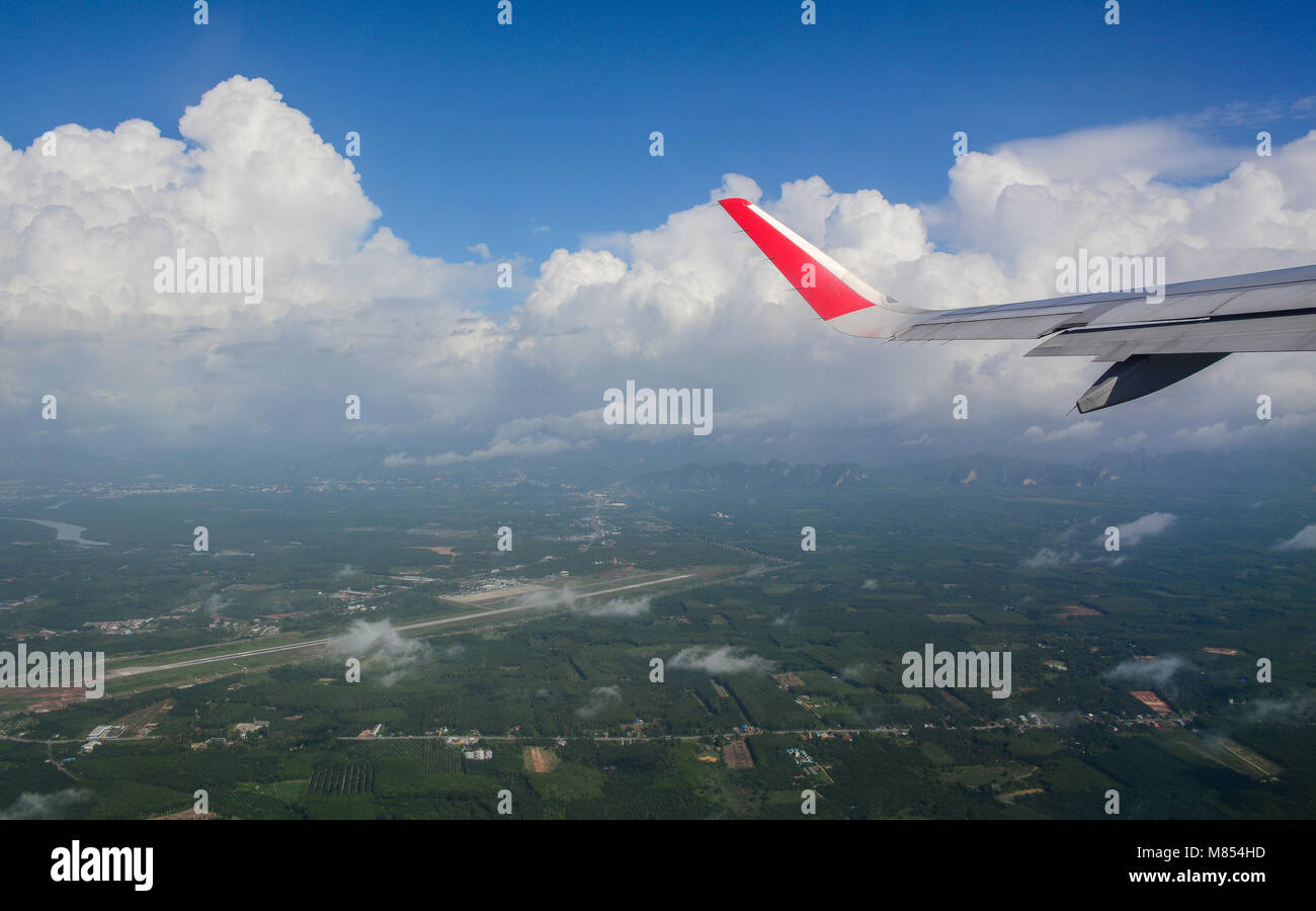 Airplane wing view. An aircraft flying over green fields Stock Photo ...