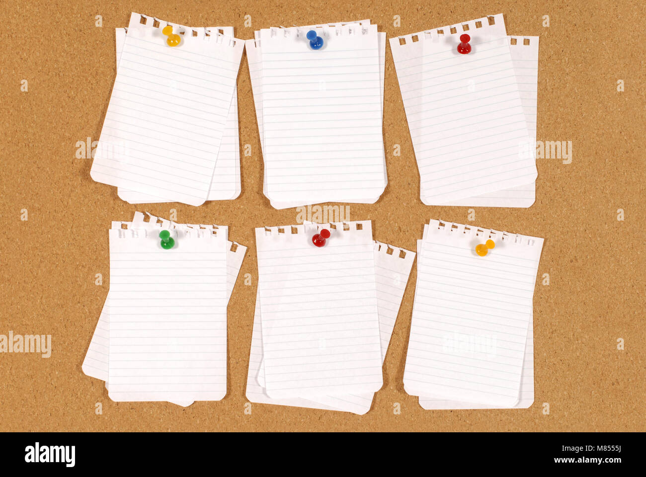 Cork notice or bulletin board with lots of blank sheets of untidy torn ...