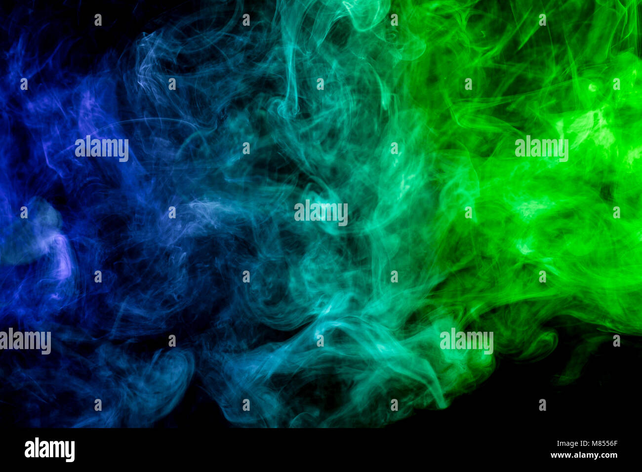 Dense multicolored smoke of blue and green colors on a black isolated ...