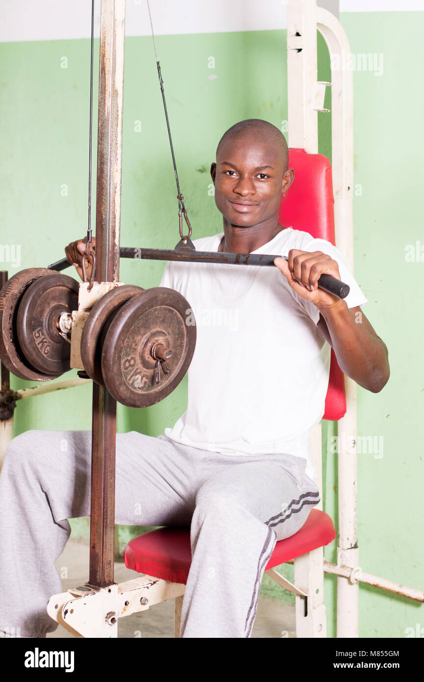 Young man doing weight training by pulling a weight by a pulley Stock ...