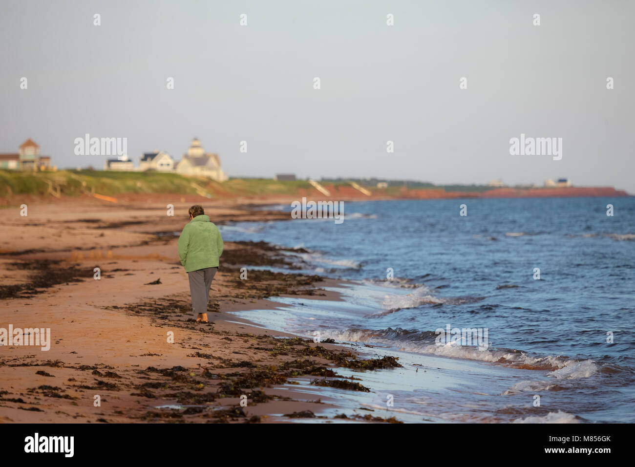 A woman walks along the shoreline of northern Prince Edward Island ...
