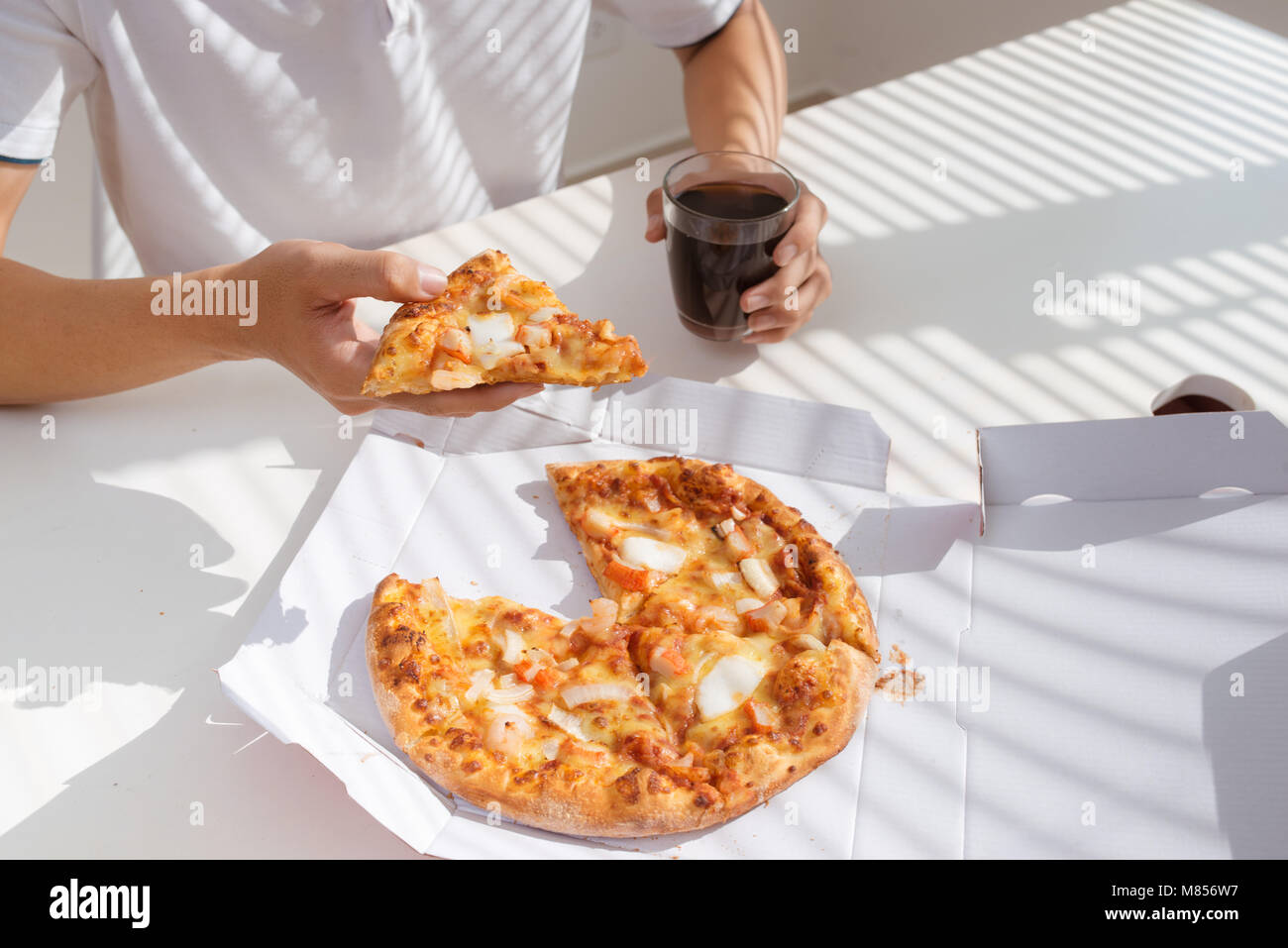close up man hand eating pizza while working in laptop computer Stock ...