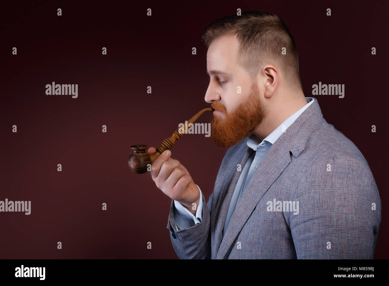 portrait of a red bearded man smoking a pipe on a brown background ...