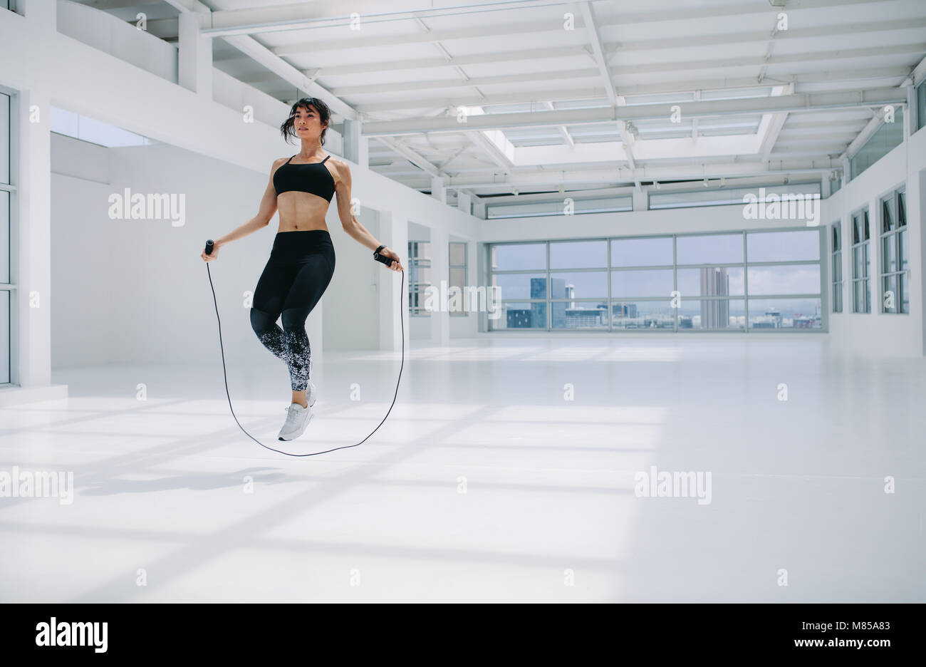 Woman exercising using skipping rope in fitness studio. Athletic woman ...
