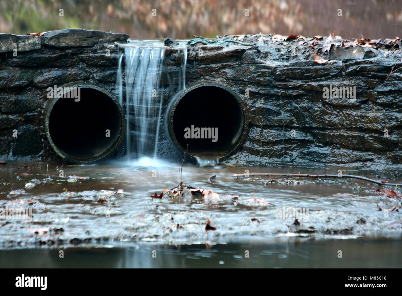 A small flowing waterfall between two pipes Stock Photo - Alamy