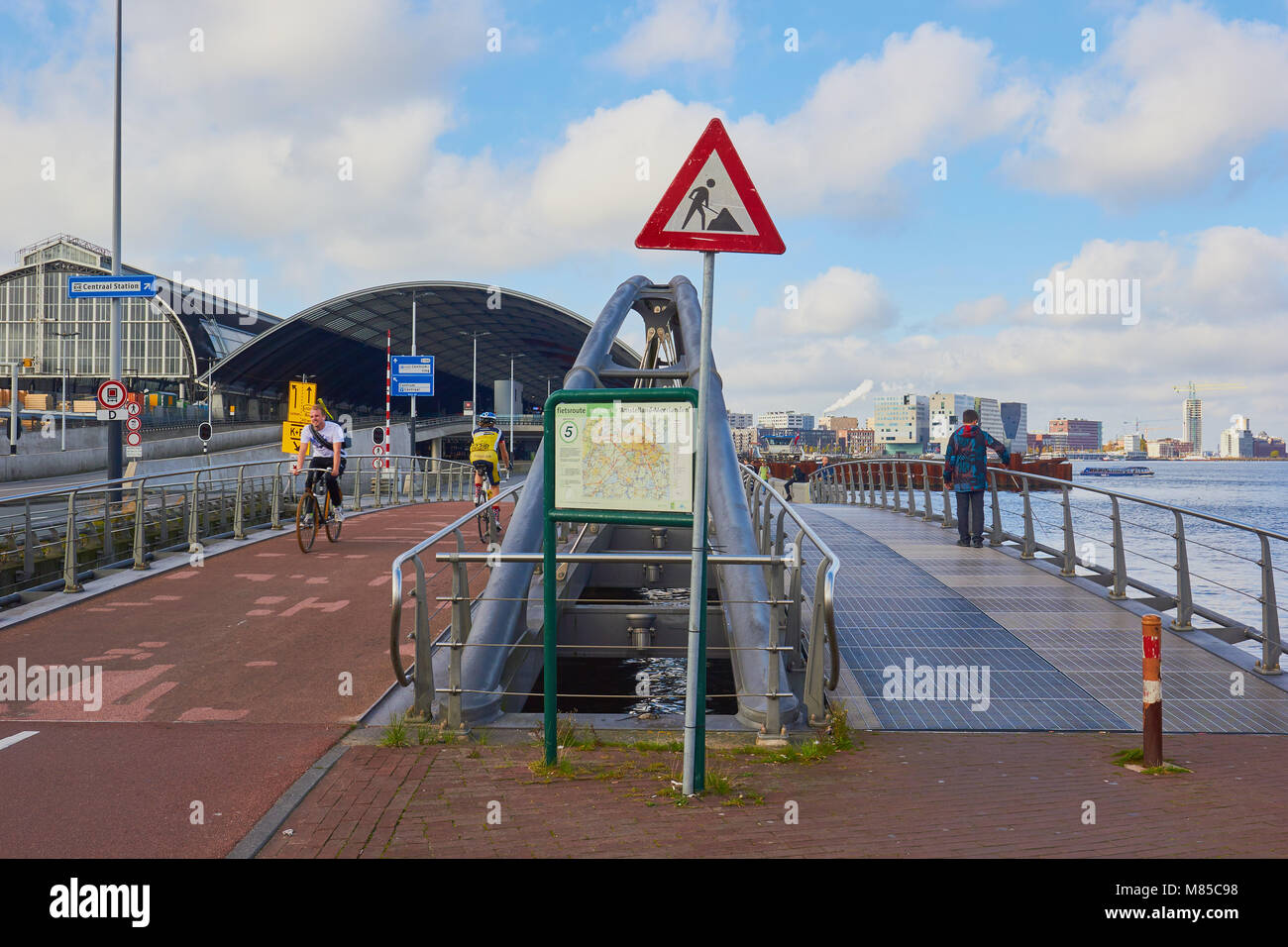 Cycle lanes next to the IJ river with Amsterdam Central Station in the ...