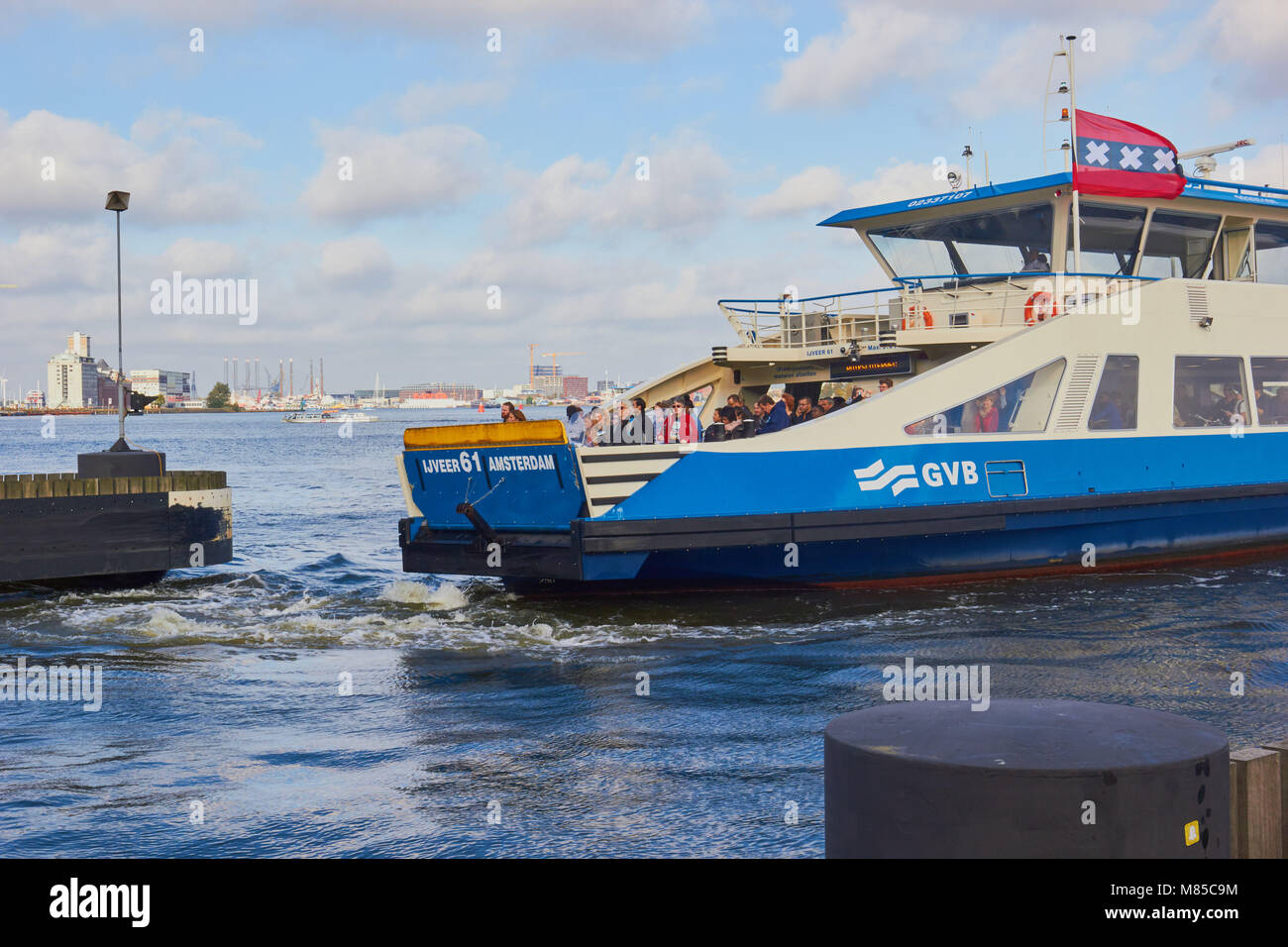 Passenger ferry flying the Amsterdam flag crossing the IJ river ...