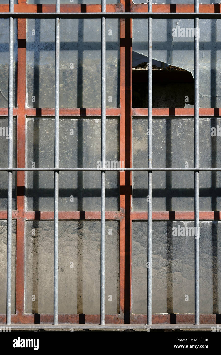 A broken window of an abandoned industrial building with barred window ...