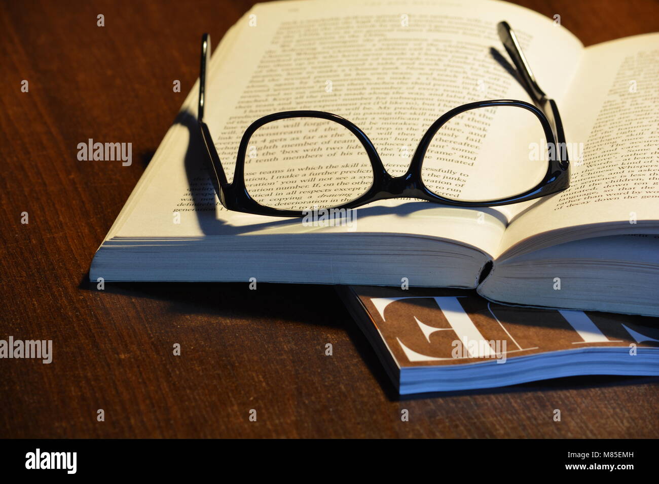Reading glasses laying on an open book Stock Photo - Alamy