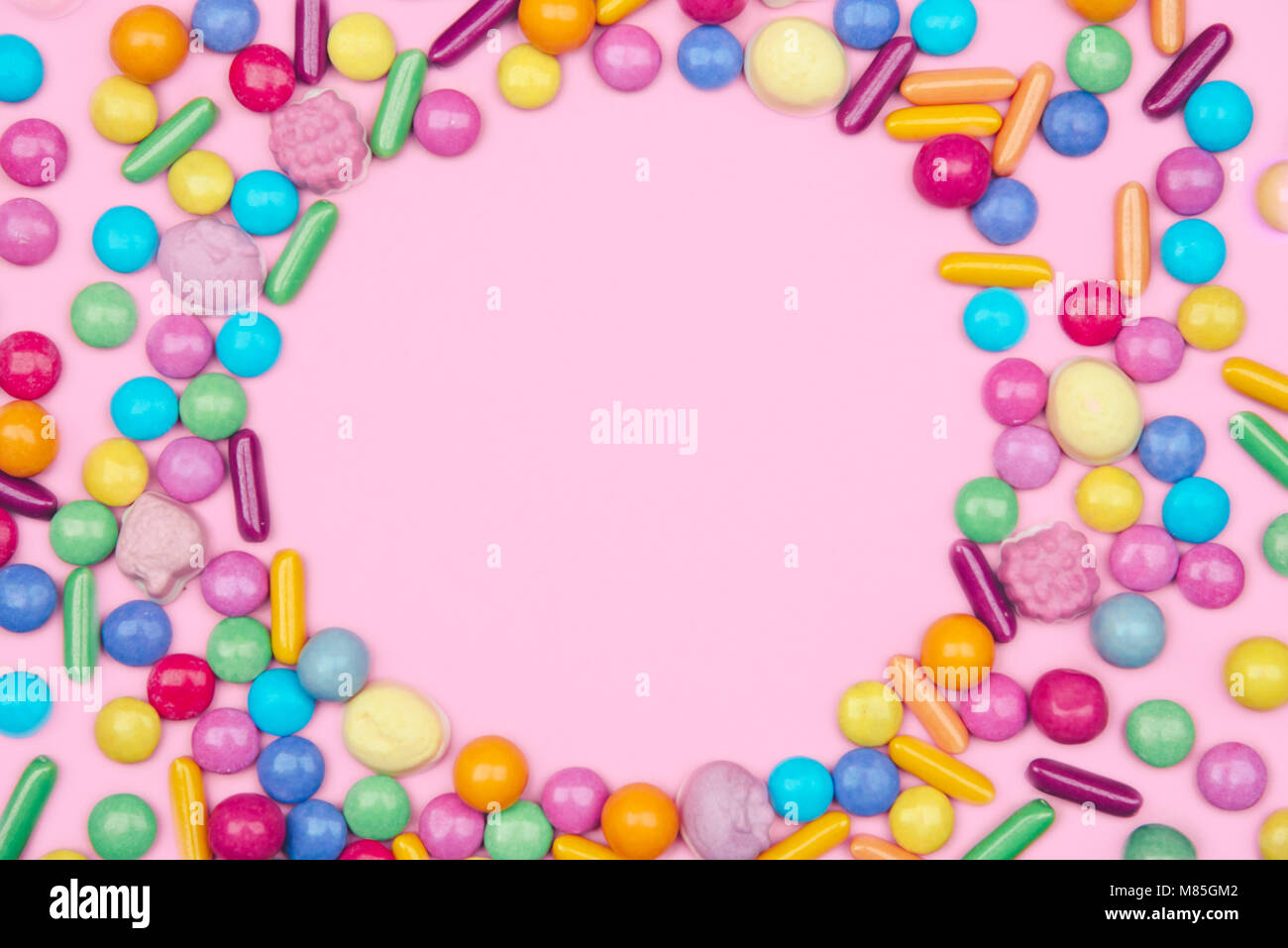 Round frame with assorted colored candies on pink background Stock ...