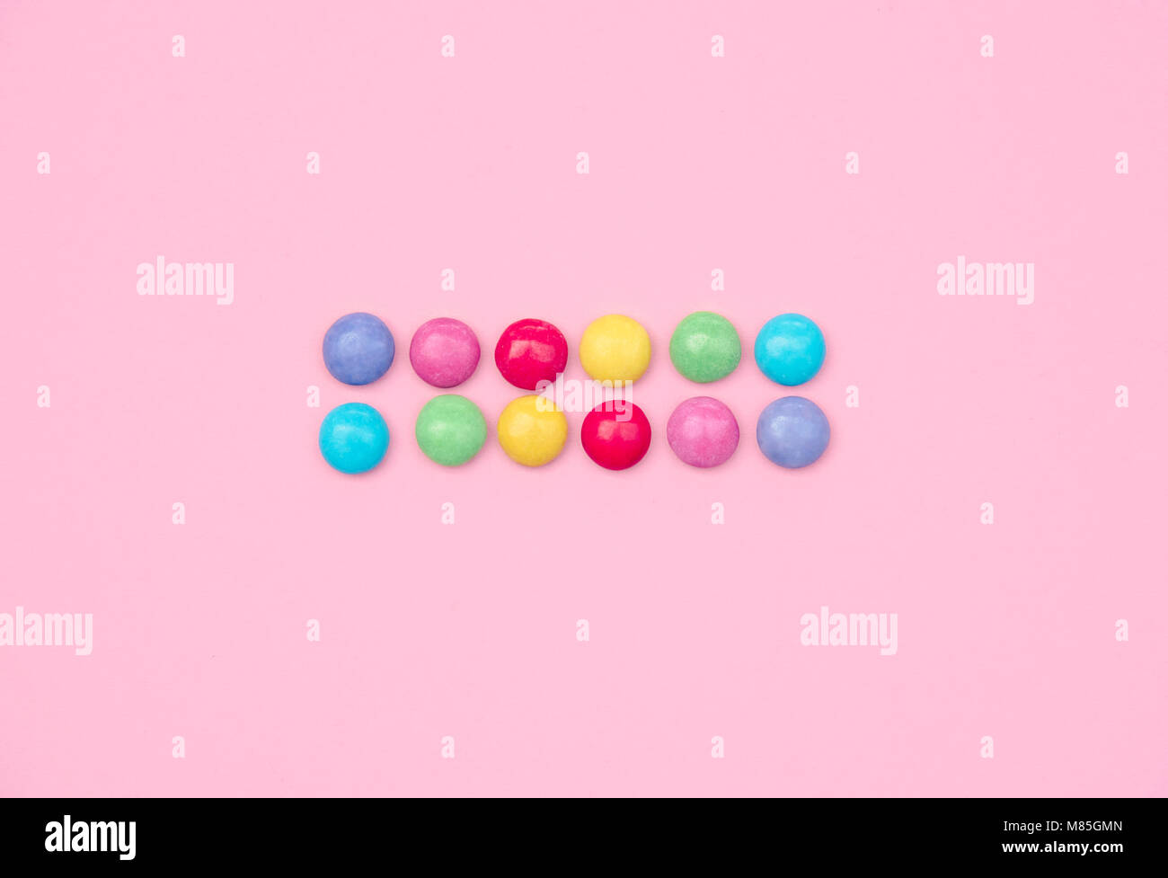 Assorted colored candies on pink background Stock Photo - Alamy