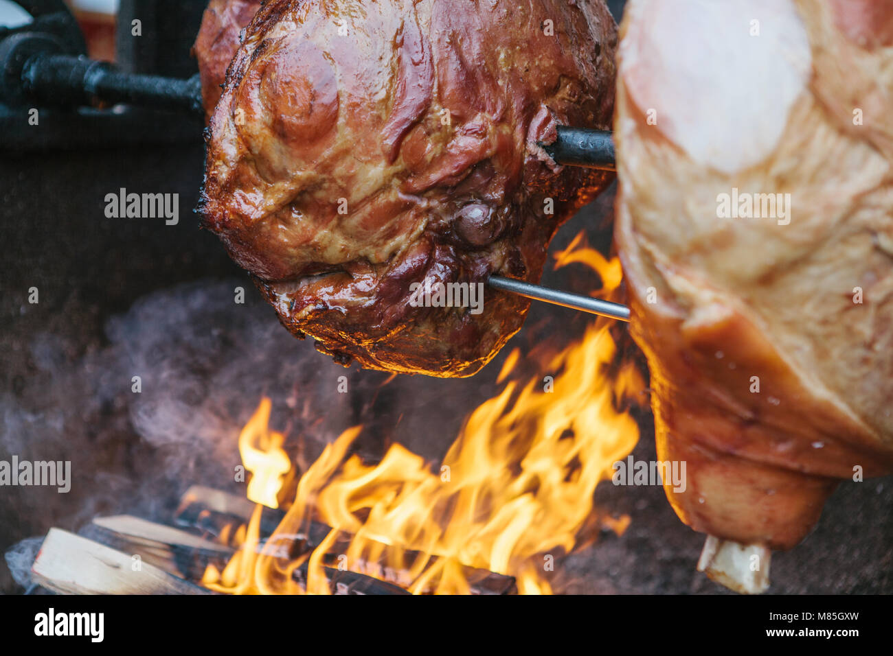 Large chunks of delicious pork hams cooked on an open fire. The street ...