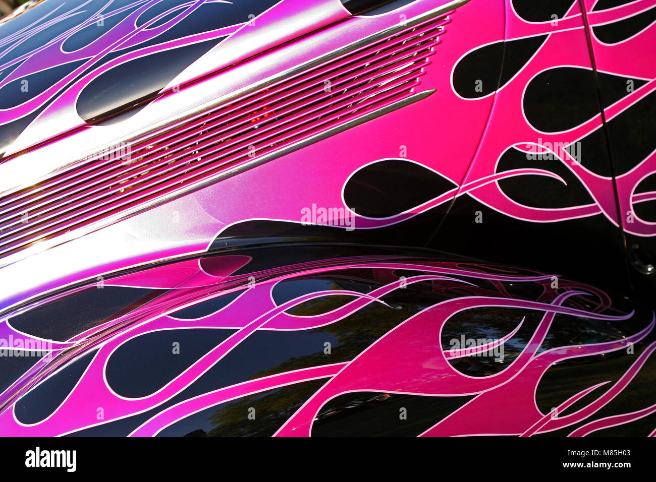 close up of a hot rods hood with pink flames runing over the hood and ...