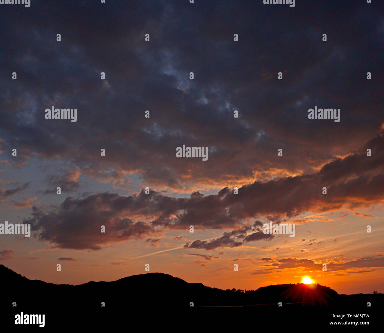 Sunset over hills with colourful clouds Stock Photo - Alamy