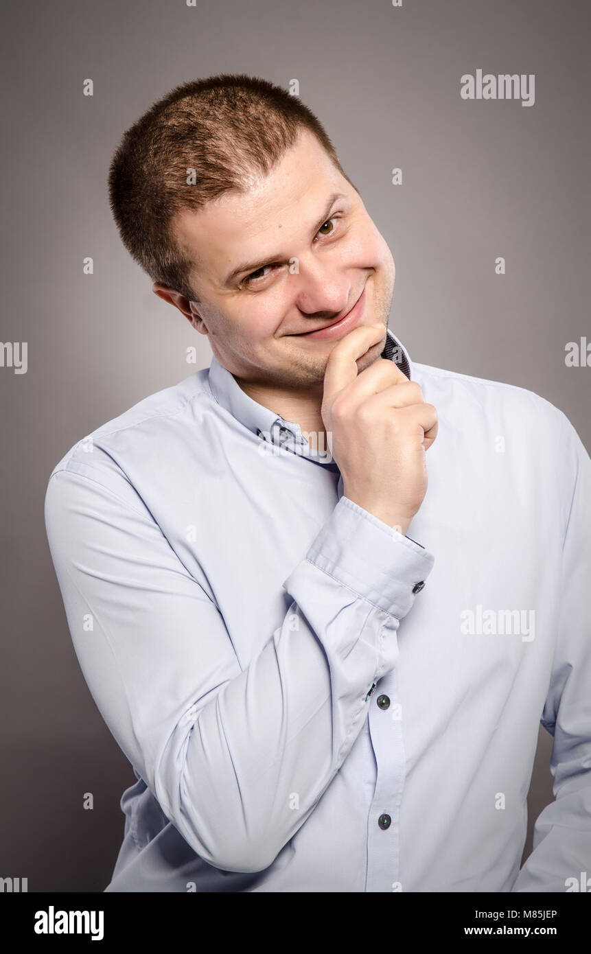young man smiling in front of grey background Stock Photo - Alamy