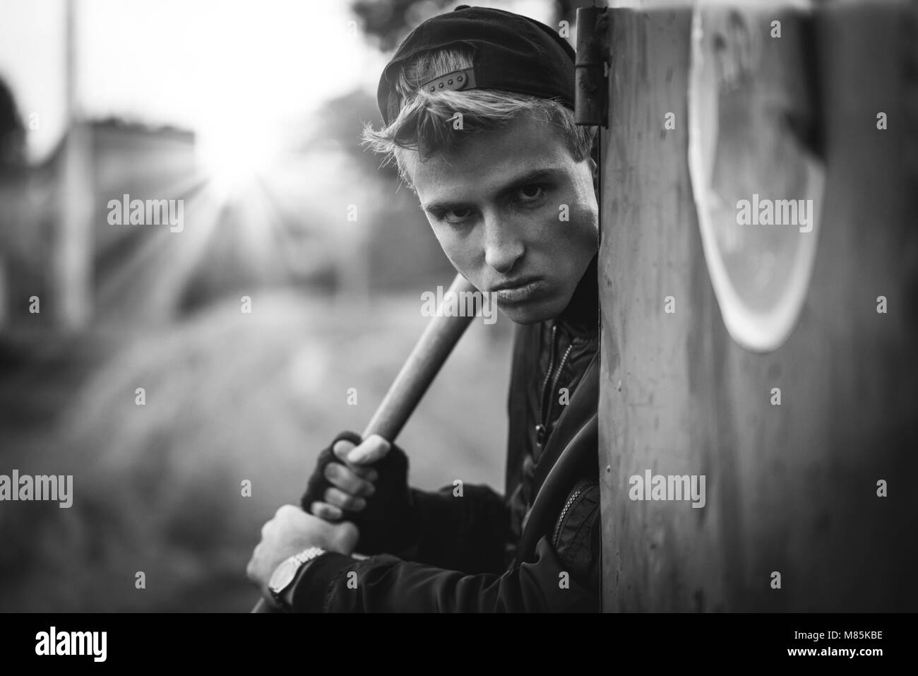 hooligan with the baseball bat in hands ready to attack from hiding ...