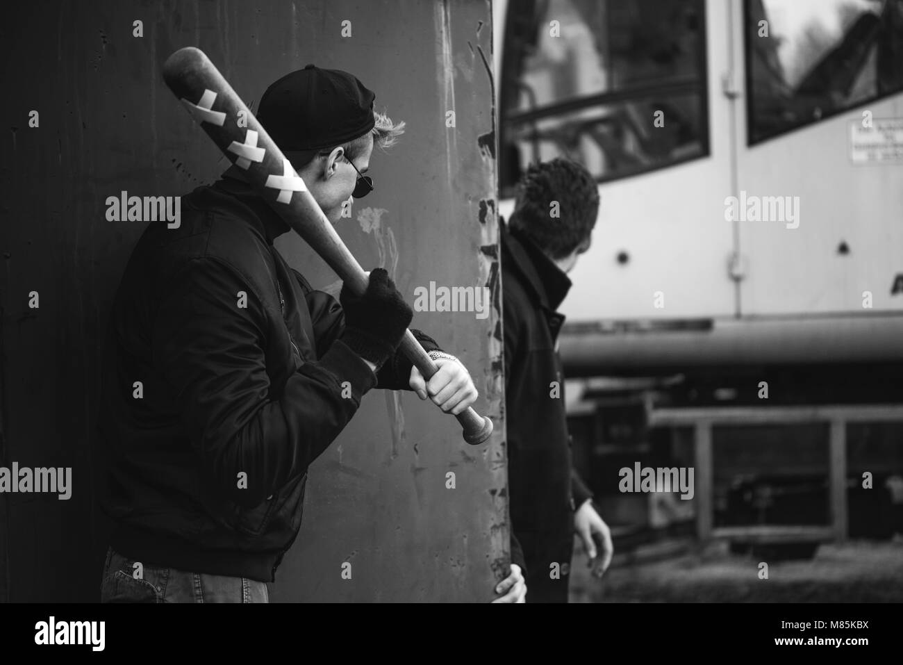 hooligan with the baseball bat in hands ready to attack from hiding ...