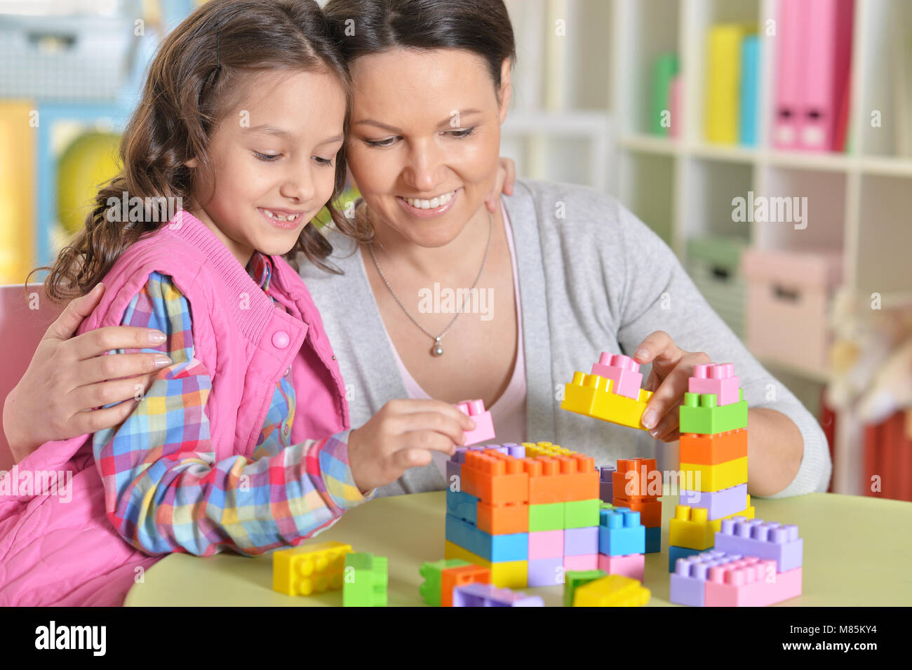 little girl and her mother playing with colorful plastic blocks Stock ...
