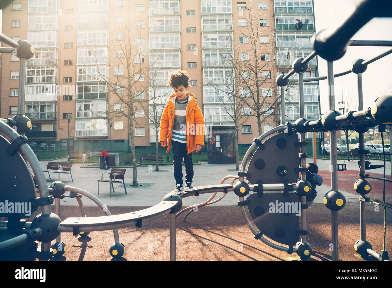 Cute little boy walking the balance bar in an urban playground in a ...