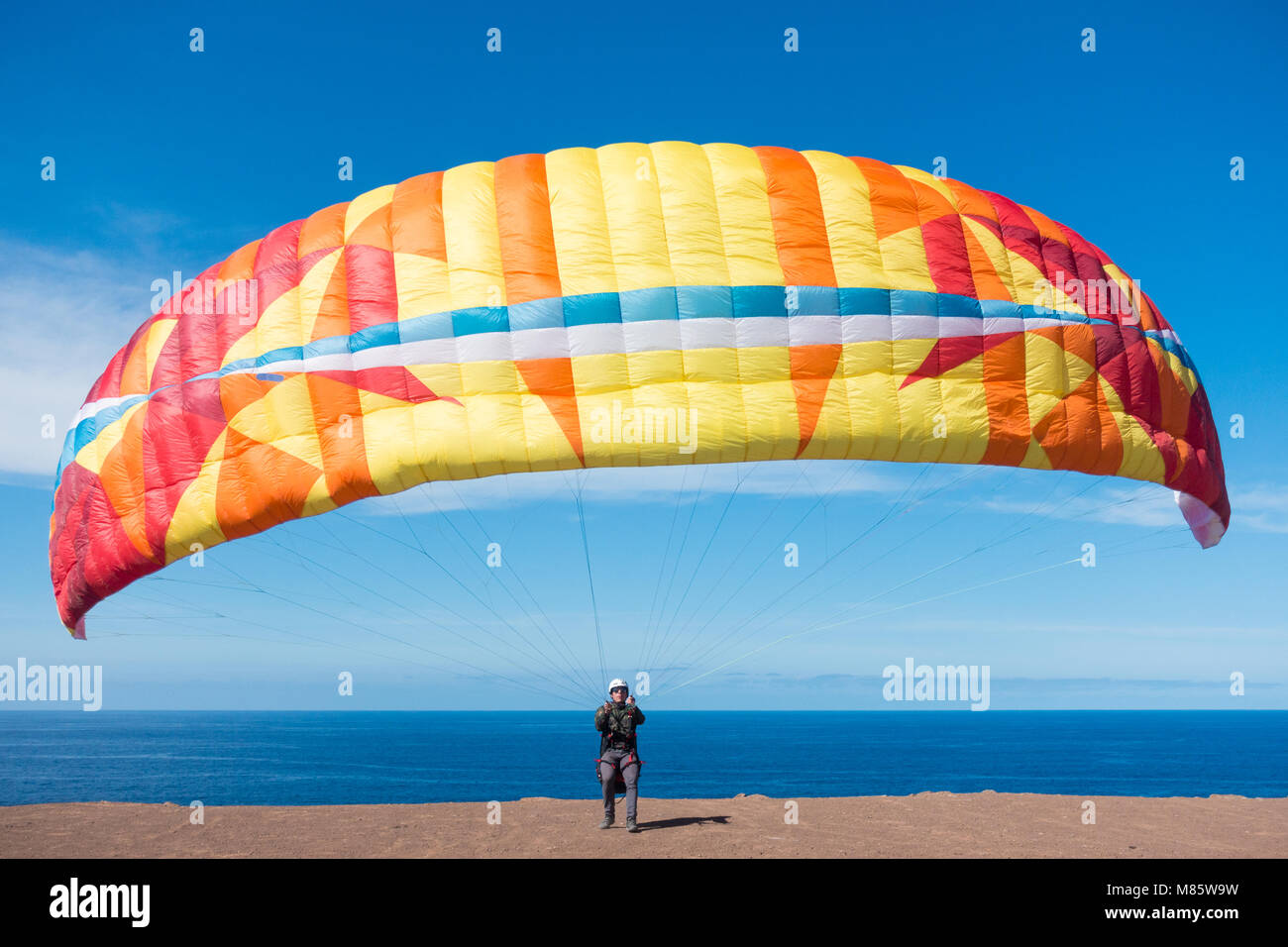 Paraglider taking off from cliff overlooking ocean. Paragliding, Gran ...