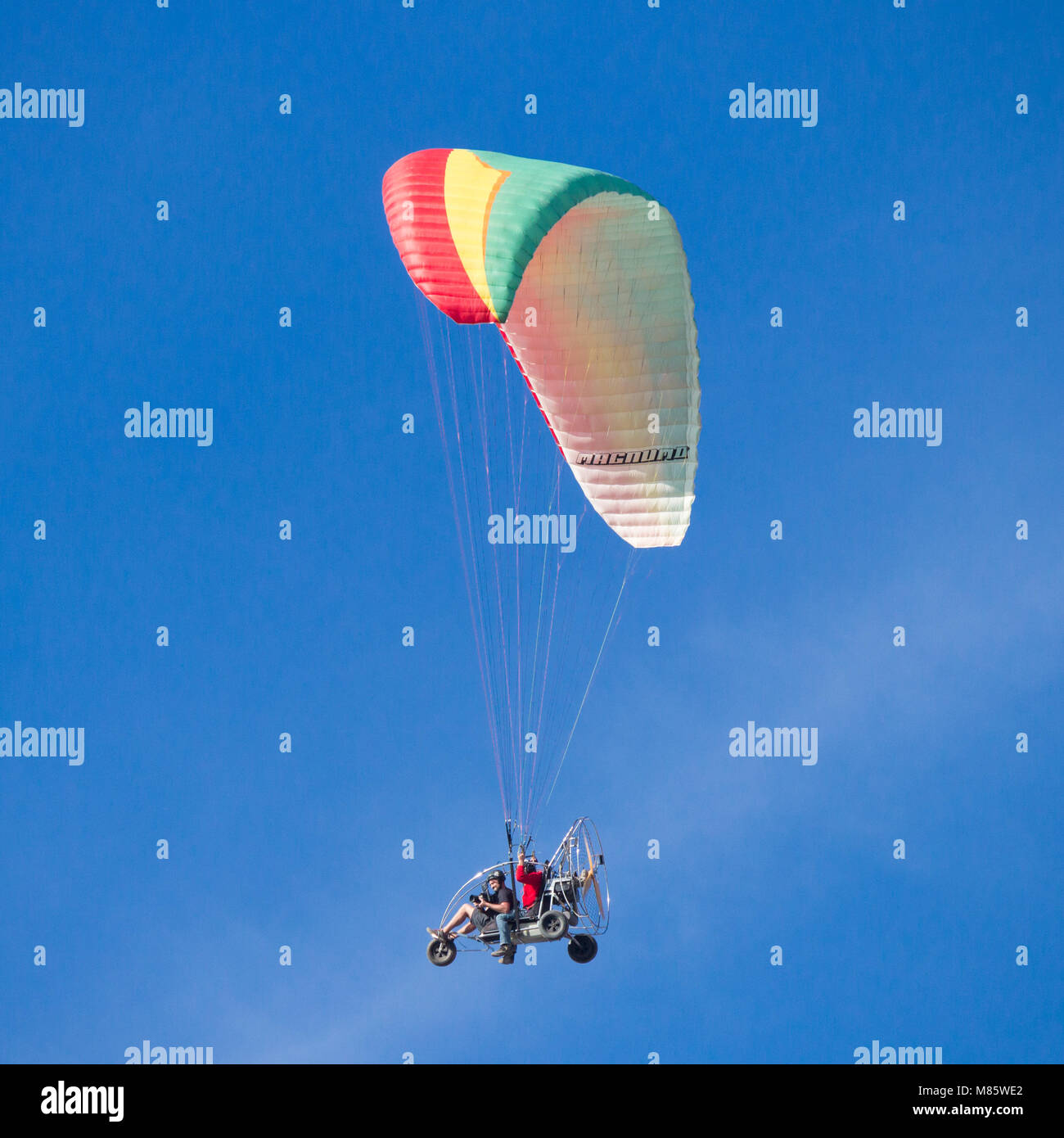 Motorized tandem paraglider against blue sky Stock Photo - Alamy
