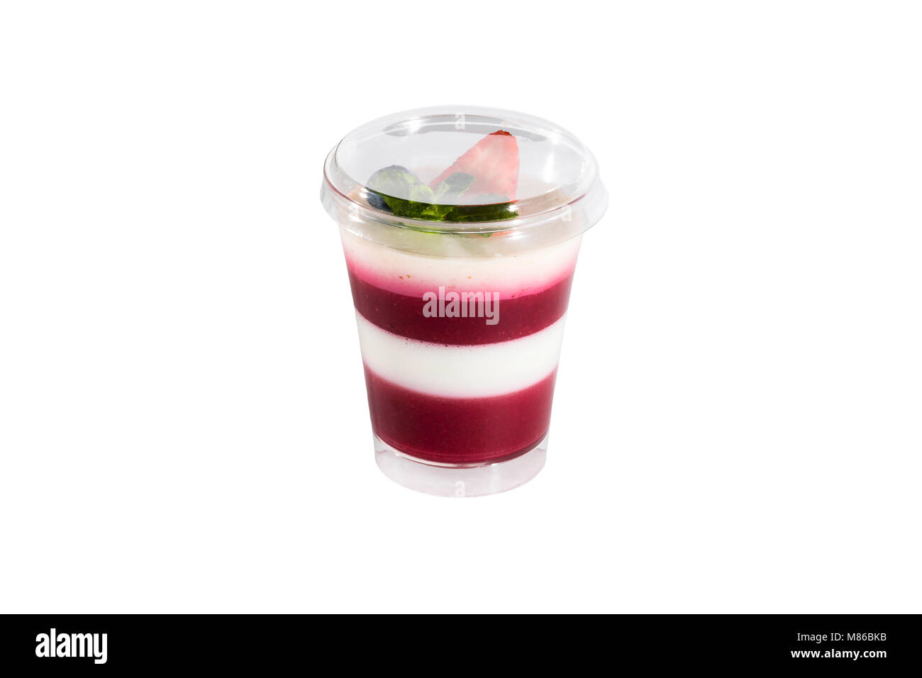 Creamy cream dessert in a plastic cup decorated with berries on a white ...