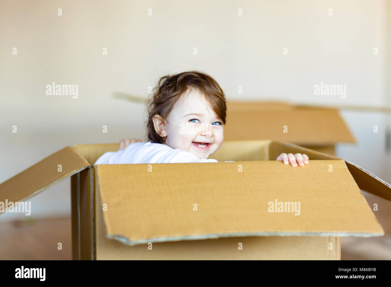 Cute smiling toddler baby girl sitting inside brown cardboard box Stock ...
