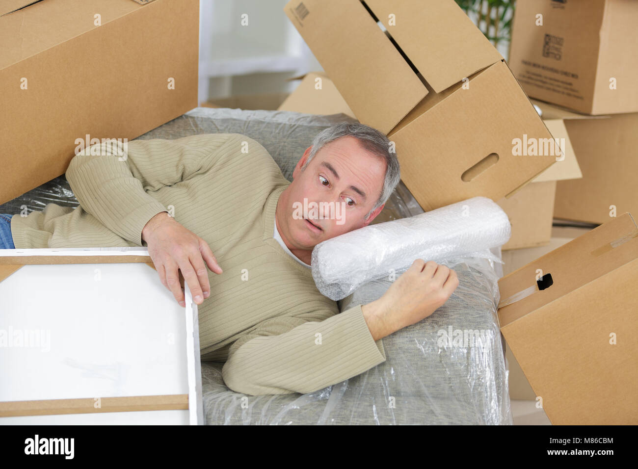 Middle aged man amidst stacks of precarious boxes Stock Photo - Alamy