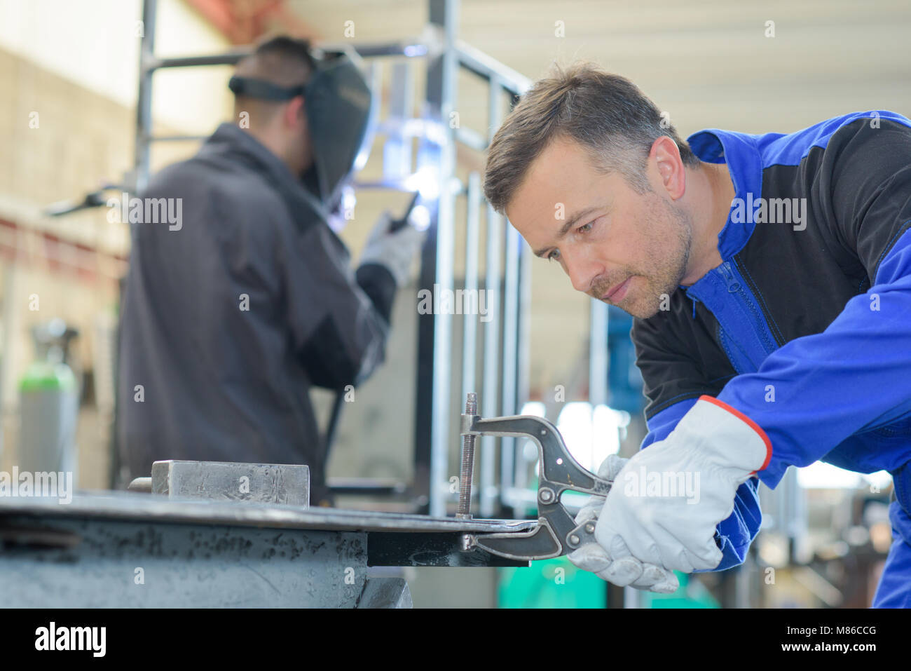 Workman fixing clamp onto bench Stock Photo - Alamy