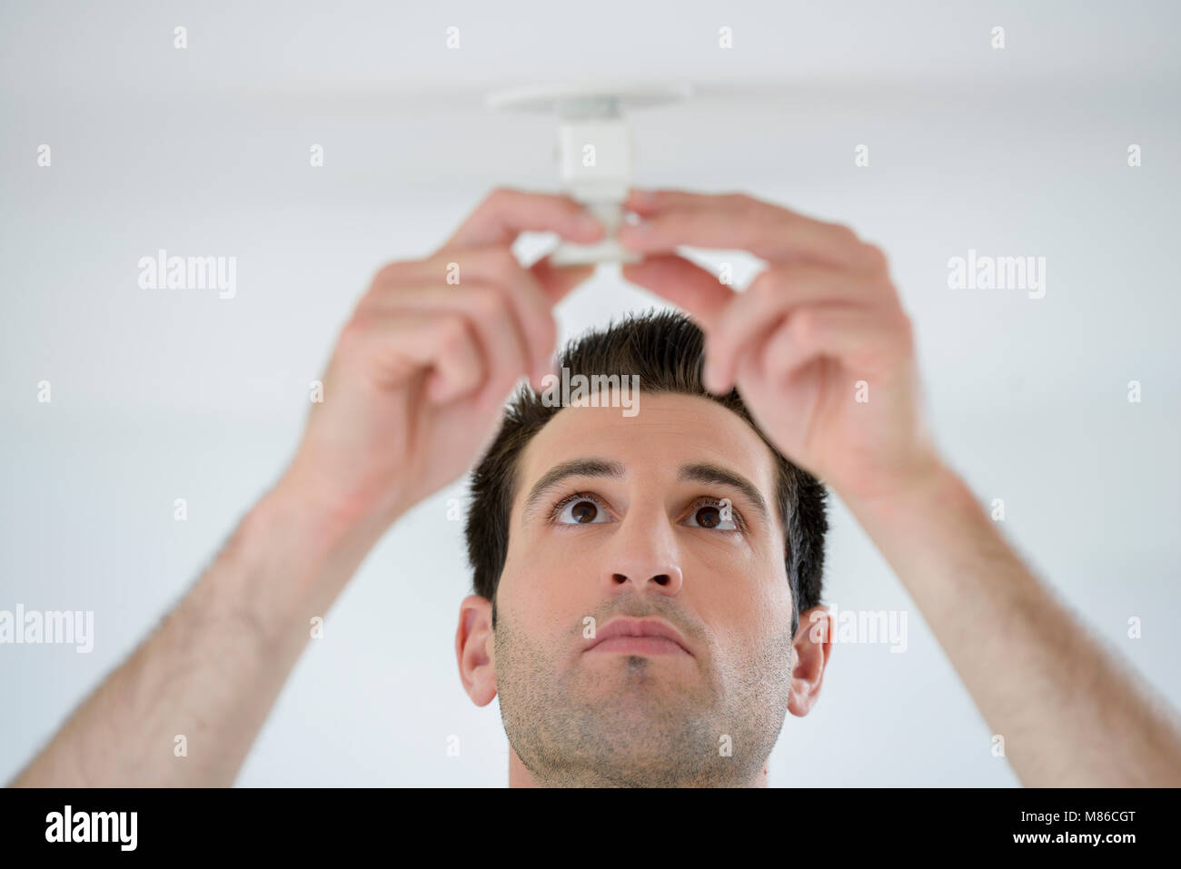 Man fitting spotlight in ceiling Stock Photo - Alamy
