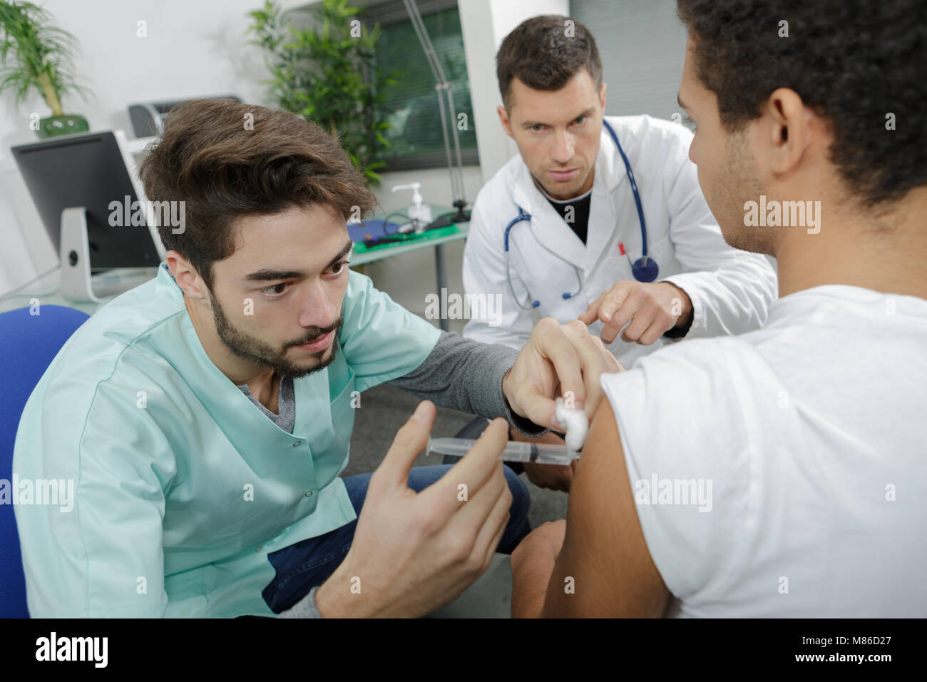 young internist doctor injecting a patient under surveillance Stock ...