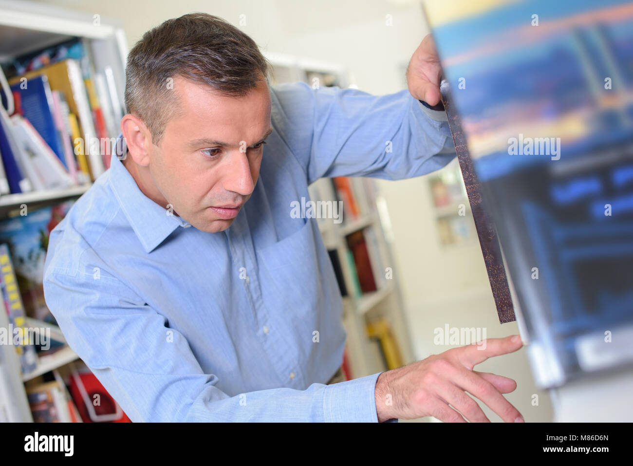 Man looking for book on library shelf Stock Photo - Alamy