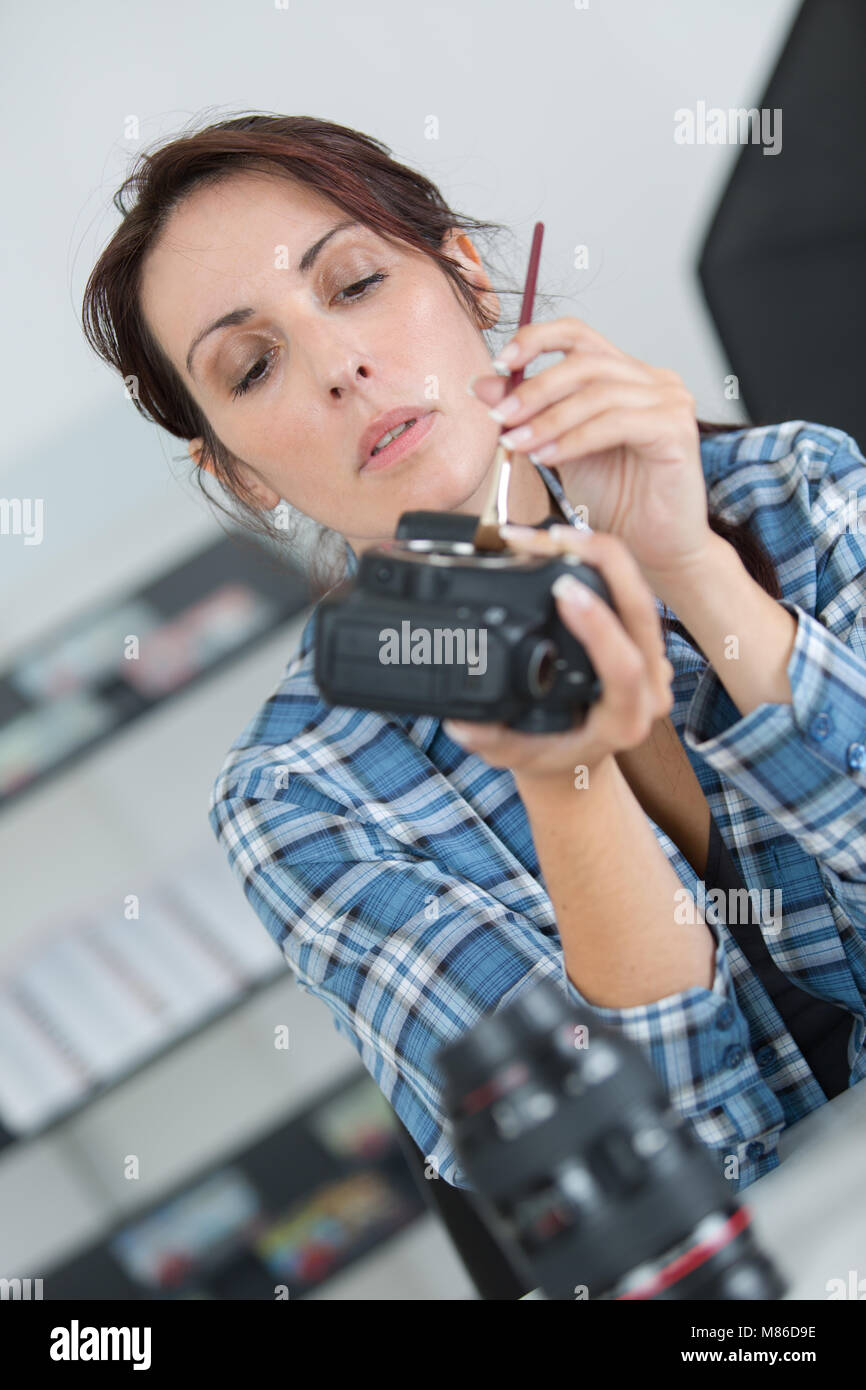 female photographer cleaning camera lens cleaning with special brush ...