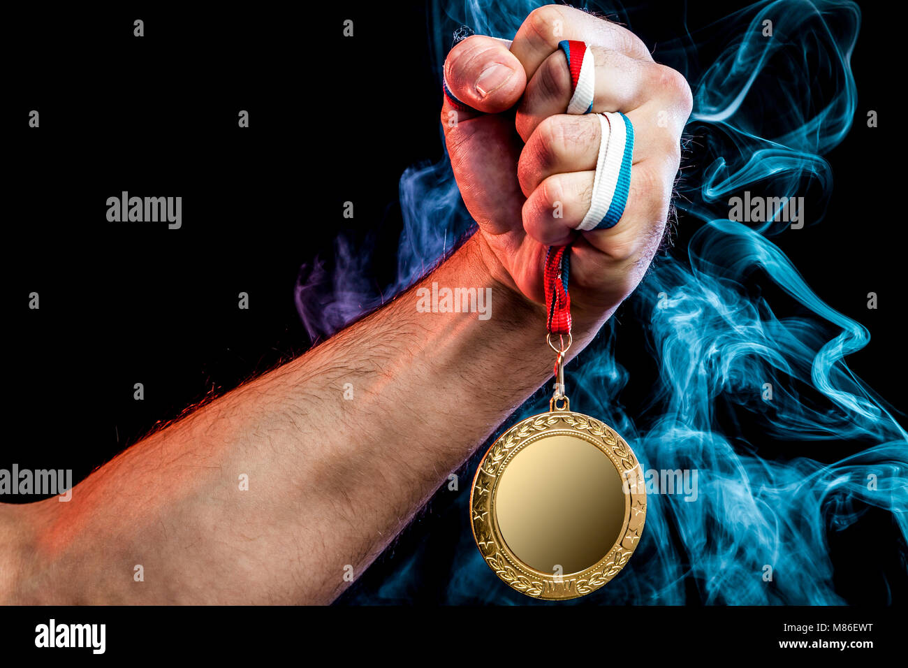Close-up of a strong male hand holding a gold medal for a sporting ...
